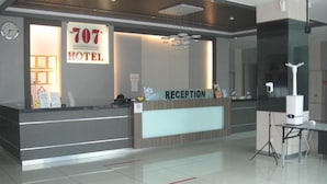 Uma área de recepção de hotel com balcão de atendimento, placa indicando a suíte 707 e um balcão de recepção.