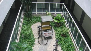 Um pátio com uma bicicleta, um triciclo e uma placa com a inscrição '707 Hotel Melaka'.