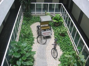 Um pátio com uma bicicleta, um triciclo e uma placa com a inscrição '707 Hotel Melaka'.