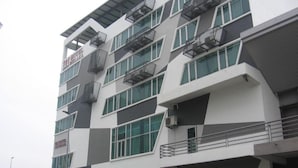 Um edifício de vários andares com varandas e grandes janelas, provavelmente um hotel ou prédio de escritórios.