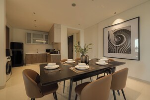 Uma zona de refeições moderna com uma mesa preta posta para quatro pessoas, rodeada por cadeiras castanhas.