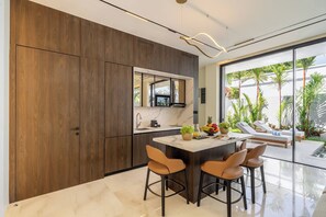 Cozinha moderna com bancada de mármore, armários de madeira e uma grande janela com vista para um jardim.
