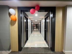 Um corredor com piso brilhante, portas em ambos os lados e um teto decorado com esferas penduradas.