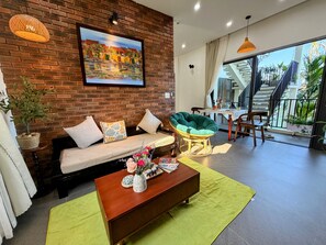 Uma sala de estar moderna com parede de tijolos, um sofá, uma mesa de centro e um espaço de jantar com uma mesa e cadeiras.