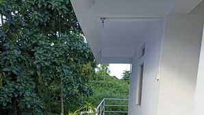 Uma varanda com piso de madeira, grade branca e unidade de ar condicionado branca.