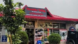 Fachada de loja com telhado vermelho e placas indicando Paradise Valley, incluindo comodidades como piscina e café.