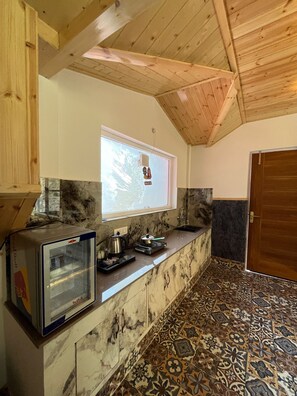 Cozinha com bancada de mármore, micro-ondas embutido e janela com vista para árvores.