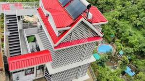Um edifício de vários andares com telhado vermelho, painéis solares e uma piscina.
