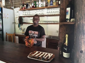 Uma pessoa parada atrás do balcão, com uma bandeja de comida e uma garrafa de champanhe.