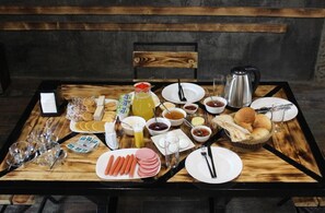 Um buffet de café da manhã com diversos alimentos e acompanhamentos em uma mesa de madeira.