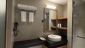 Uma casa de banho moderna com lavatório, espelho, porta-toalhas e cabine de duche em vidro.