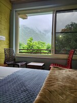 Um quarto com uma cama, uma janela, uma cadeira e uma mesa.