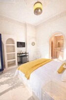 Quarto de hotel com cama, escrivaninha, cadeira e televisão.