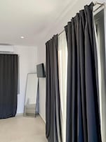 Um quarto com um espelho grande, uma televisão de tela plana e uma cortina.
