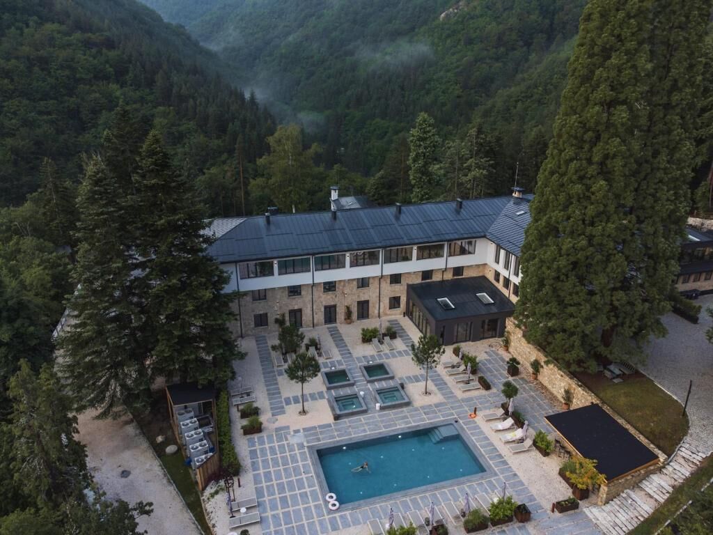 Um hotel com piscina, área de estar externa e montanhas ao fundo.