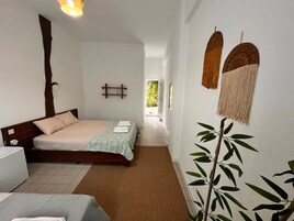 Quarto de hotel com cama, mesa de cabeceira e vista para o corredor.