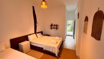 Quarto de hotel com cama, mesas de cabeceira, luminária pendente e vista para o exterior.