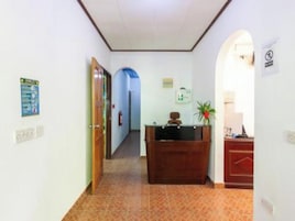 Um corredor com uma mesa de recepção, um extintor de incêndio e uma placa na parede.