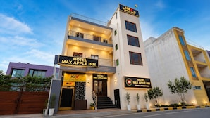 Um hotel moderno com uma placa chamativa para 'Hotel Max Apple Inn' e uma entrada visível.