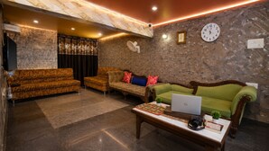 Uma sala de estar moderna com parede de pedra, um sofá verde, um sofá com estampa de tigre e uma mesa de centro com um laptop.