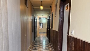 Um corredor com piso estampado, portas em ambos os lados e um lustre.