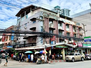 Um edifício com vários andares e diversas lojas no andar térreo, incluindo uma farmácia e um restaurante.