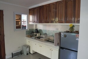Uma cozinha com armários de madeira, micro-ondas embutido, geladeira e uma janela com vista para o exterior.