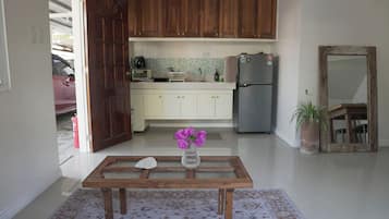 Uma cozinha com armários de madeira, geladeira, micro-ondas e uma mesa com um vaso de flores.