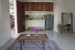 Uma cozinha com armários de madeira, geladeira, micro-ondas e uma mesa com um vaso de flores.