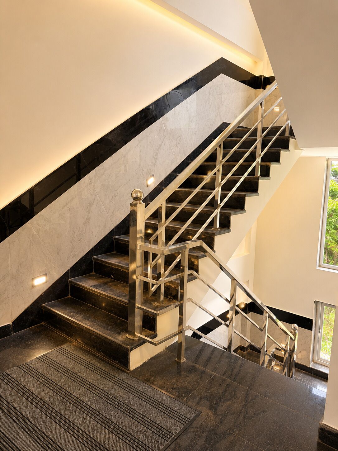 Uma escadaria moderna com corrimão de metal e um hall forrado com carpete.