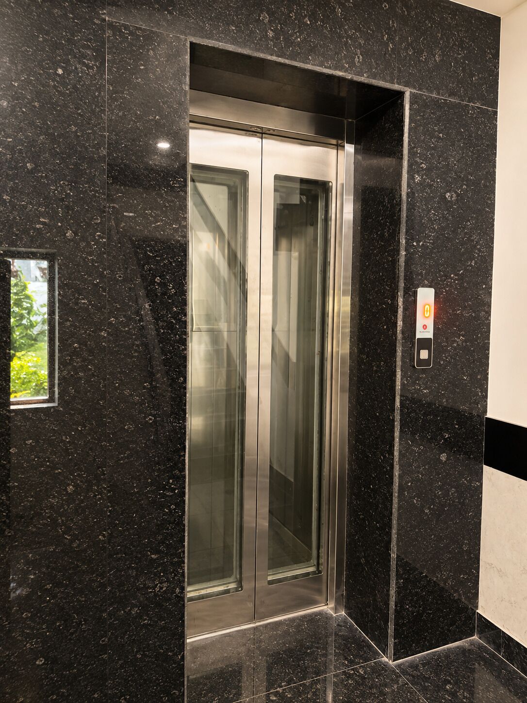 Um elevador moderno com portas metálicas e um painel de controle na parede.