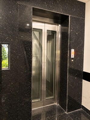 Um elevador moderno com portas metálicas e um painel de controle na parede.