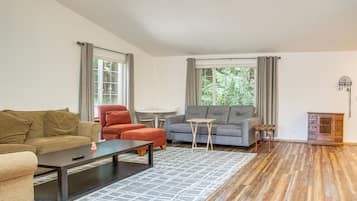 Uma sala de estar com sofá, poltrona, mesa de centro e uma mesinha lateral.