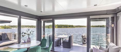 Um interior moderno com área de jantar, assentos e vista para um lago.