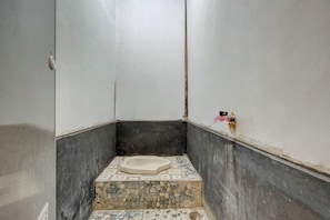 Casa de banho pequena e fechada, com banheira, secador de mãos e chão em azulejo.