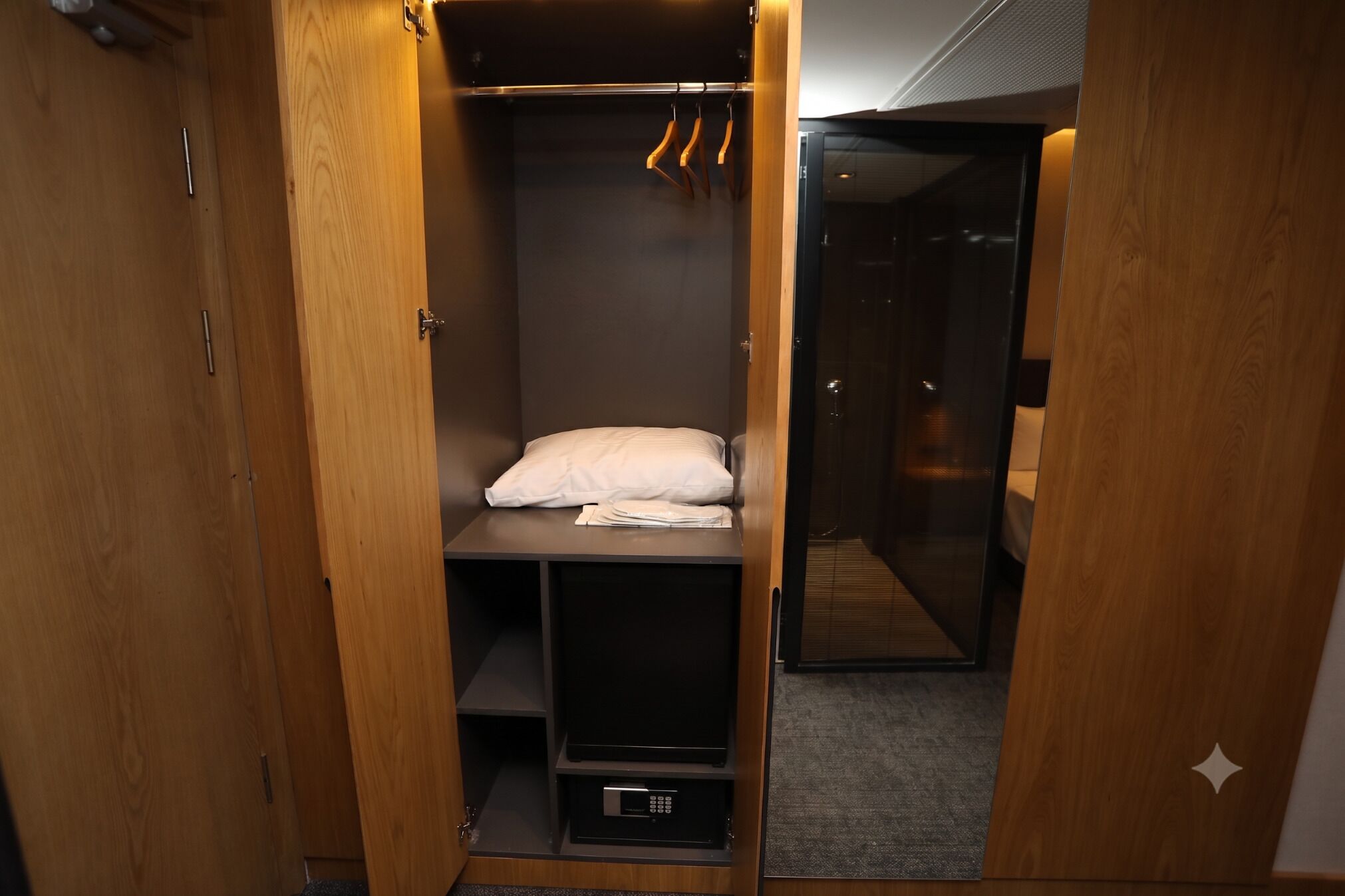 Um closet compacto com cama, uma prateleira pequena e um móvel para guardar objetos.