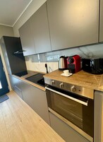 Cozinha compacta com forno embutido, cafeteira e torradeira.