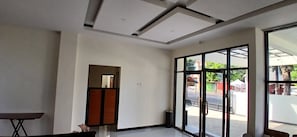 Quarto com uma grande porta de vidro deslizante que dá para uma área externa, uma pequena mesa e um espelho na parede.
