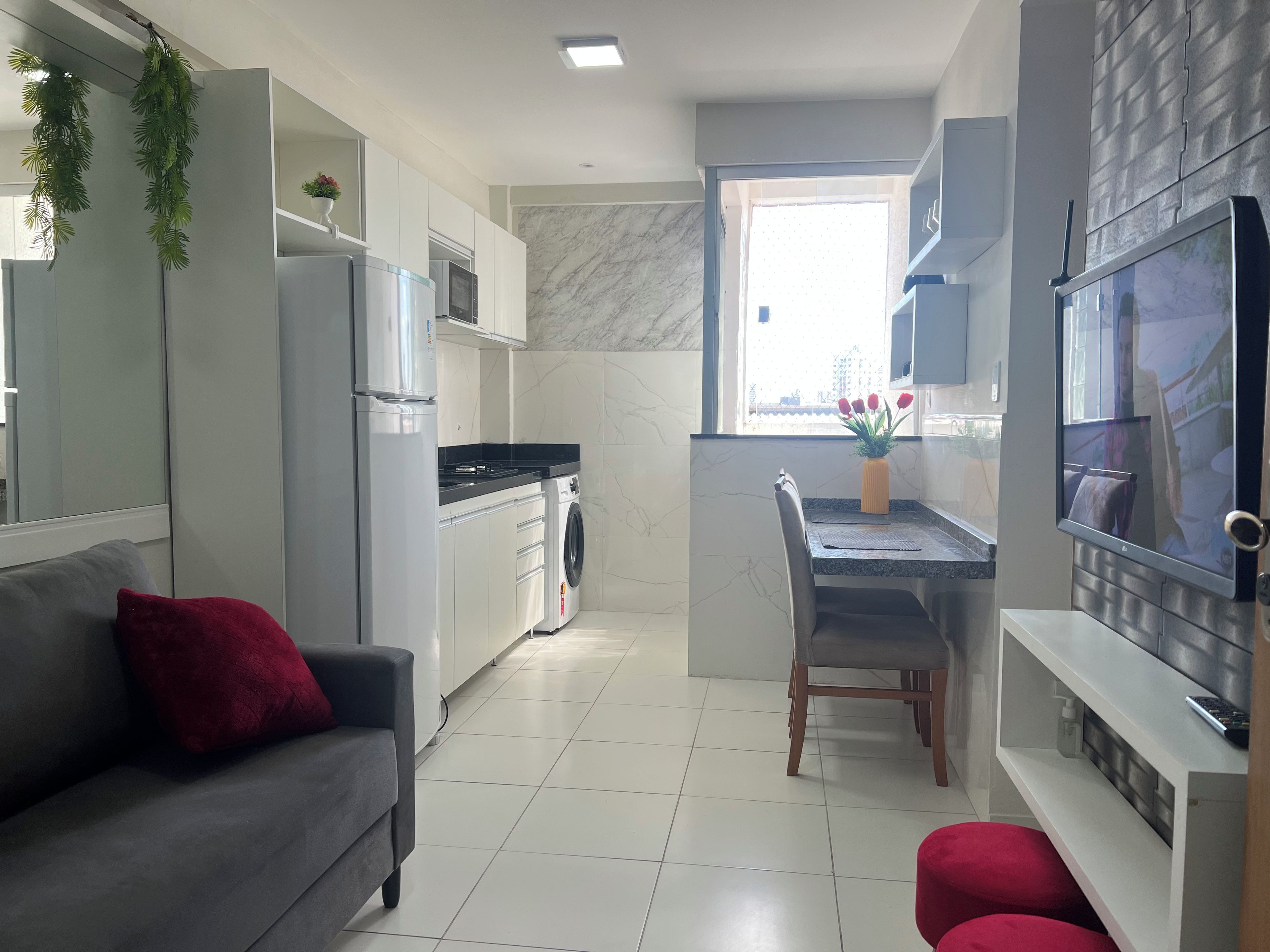 Cozinha moderna com área de refeições, sofá e televisão.