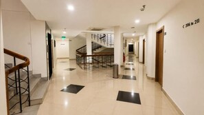 Corredor de hotel com escada, extintor de incêndio e placa indicando os números de quartos 206 a 211.