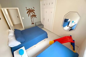 Um quarto com cama, guarda-roupa, espelho e uma cadeira pequena.