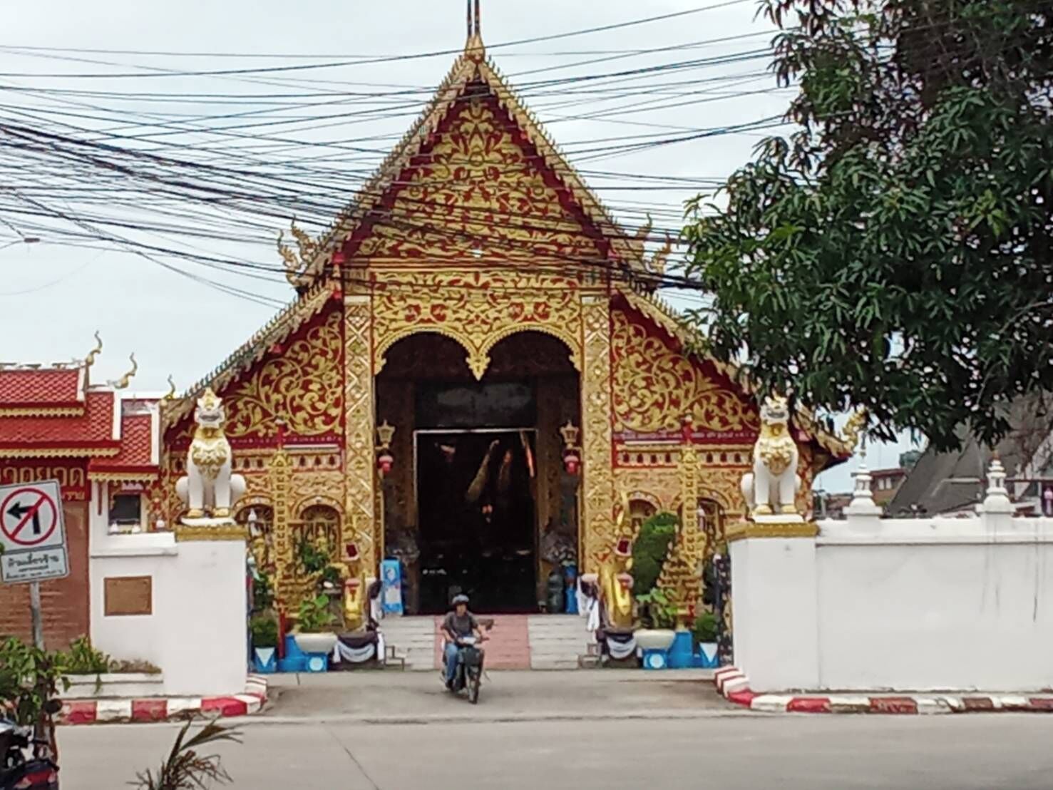 Entrada de um templo com detalhes dourados elaborados e um telhado tradicional tailandês.