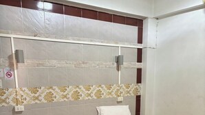 Quarto de hotel com duas camas, parede revestida de azulejos, borda estampada e parede branca com placa de proibido fumar.