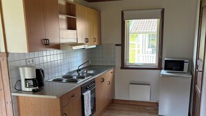 Uma cozinha compacta com armários de madeira, forno embutido, cafeteira e micro-ondas.