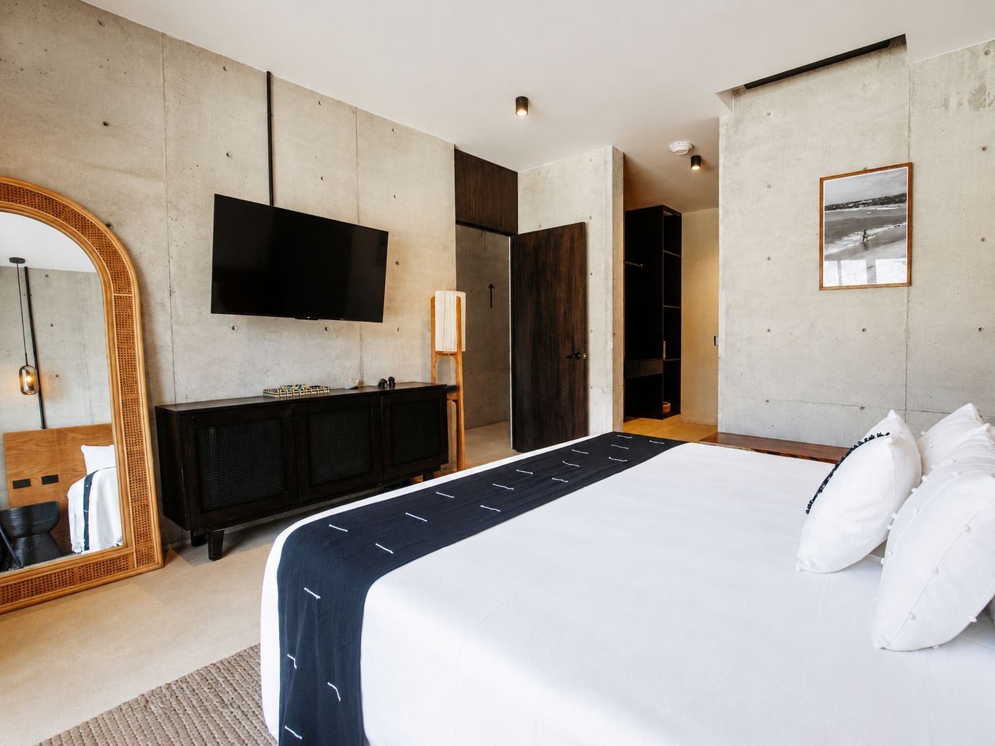Quarto moderno com uma cama grande, televisão de tela plana, guarda-roupa e espelho.