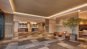 Um lobby moderno com balcão de check-in, área de estar e mesa de recepção.