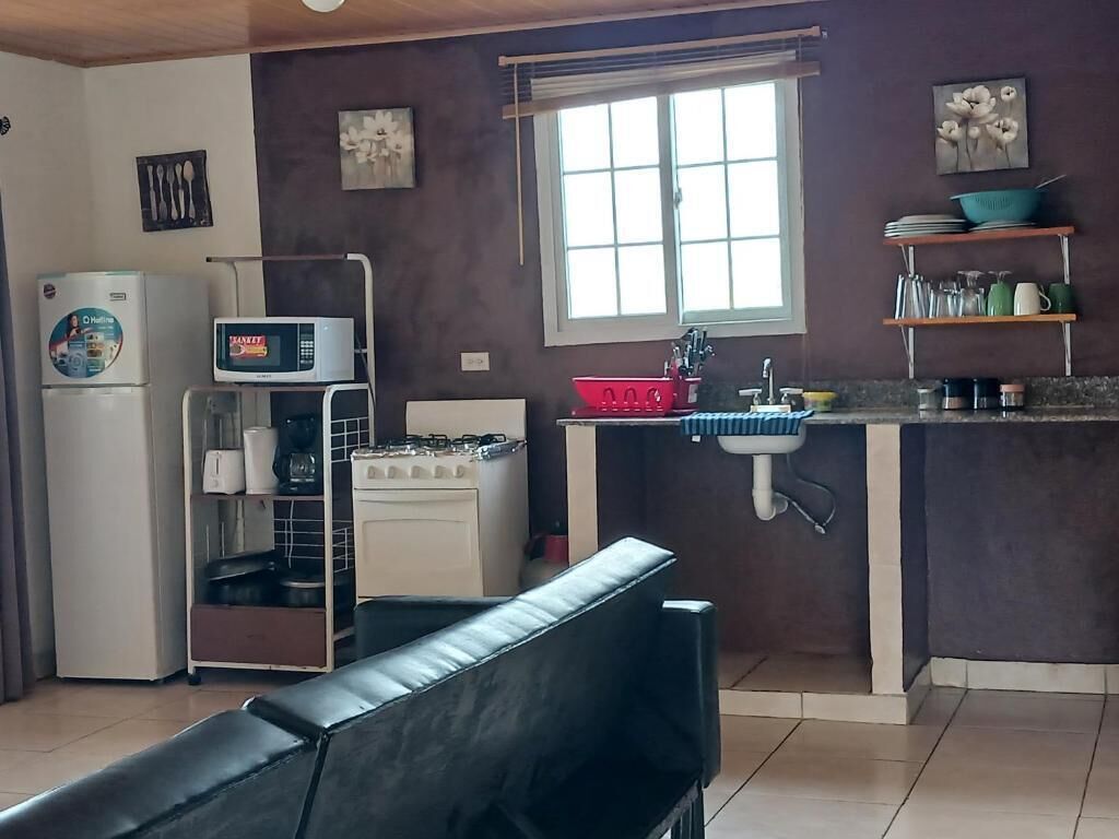 Uma cozinha compacta com fogão a gás, micro-ondas e pia.