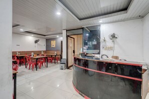 Interior de restaurante com balcão, cadeiras vermelhas e piso de azulejos.