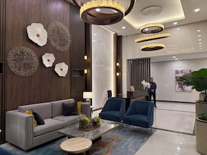 Um lobby moderno com um sofá, cadeiras, um balcão de recepção e arte decorativa na parede.