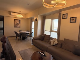Uma sala de estar moderna com sofá, mesa de centro e área de jantar com cadeiras e mesa.